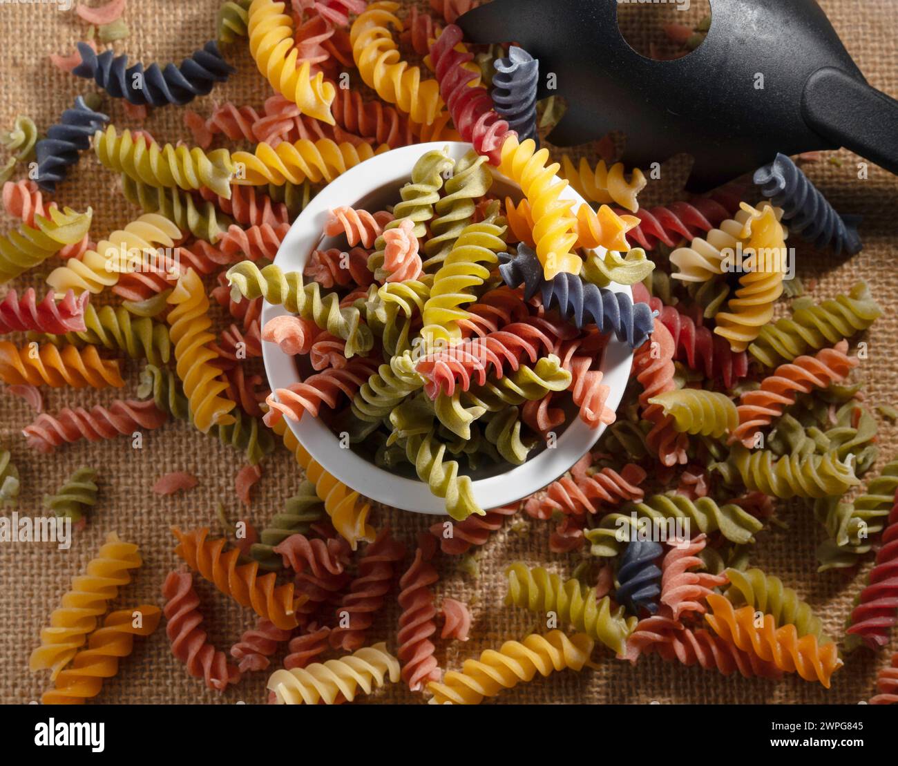 Colorful pasta spread on a table next to utensils Stock Photo - Alamy