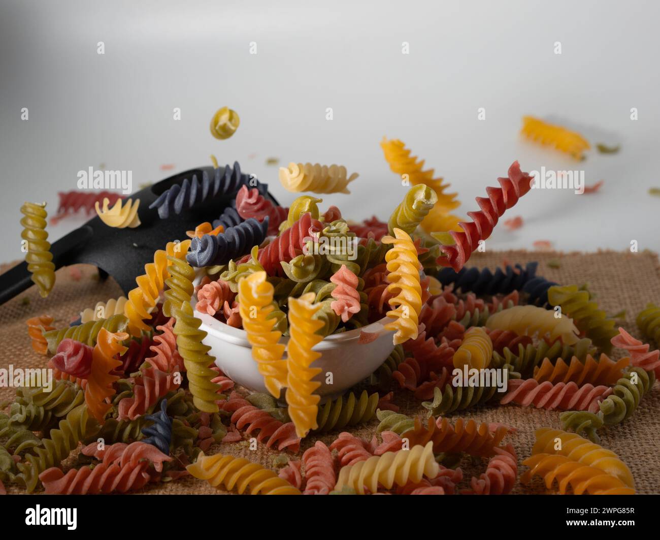 Colorful pasta spread on a table next to utensils Stock Photo - Alamy