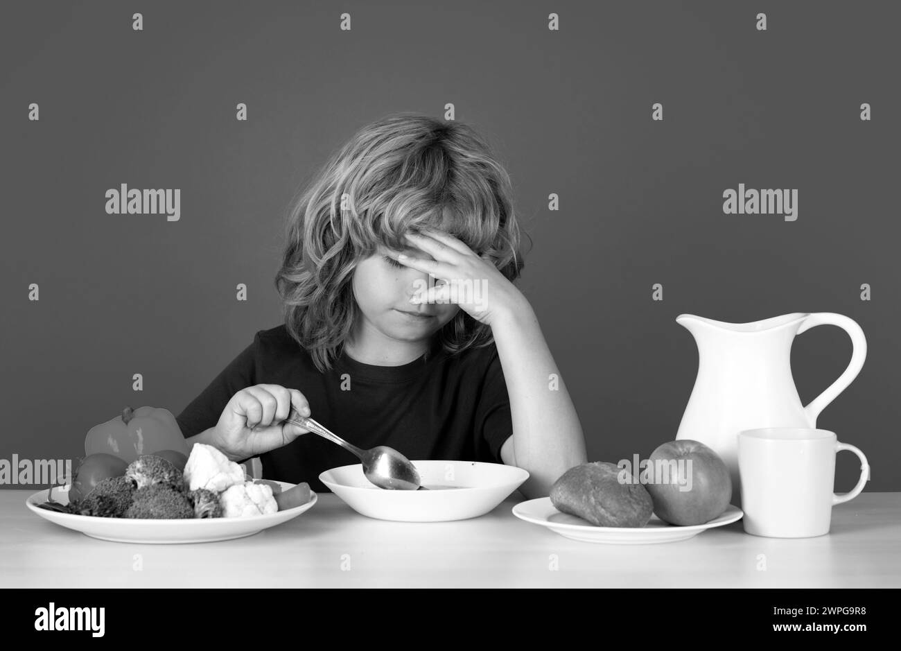 Bad appetite. Sad kid eating healthy food on studio iosolated ...