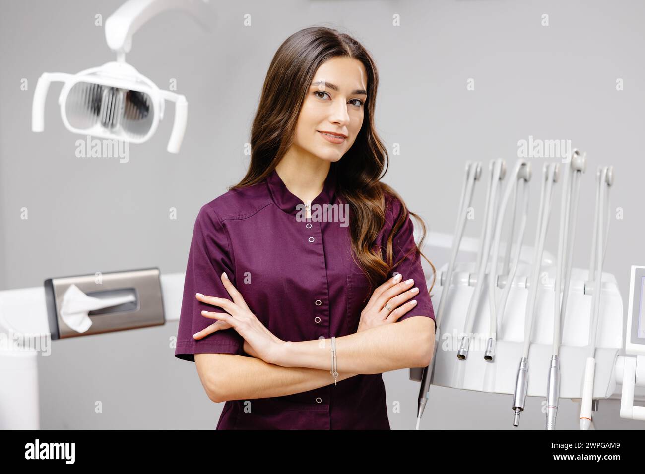 A young pretty female dentist is standing by the dental chair in the ...