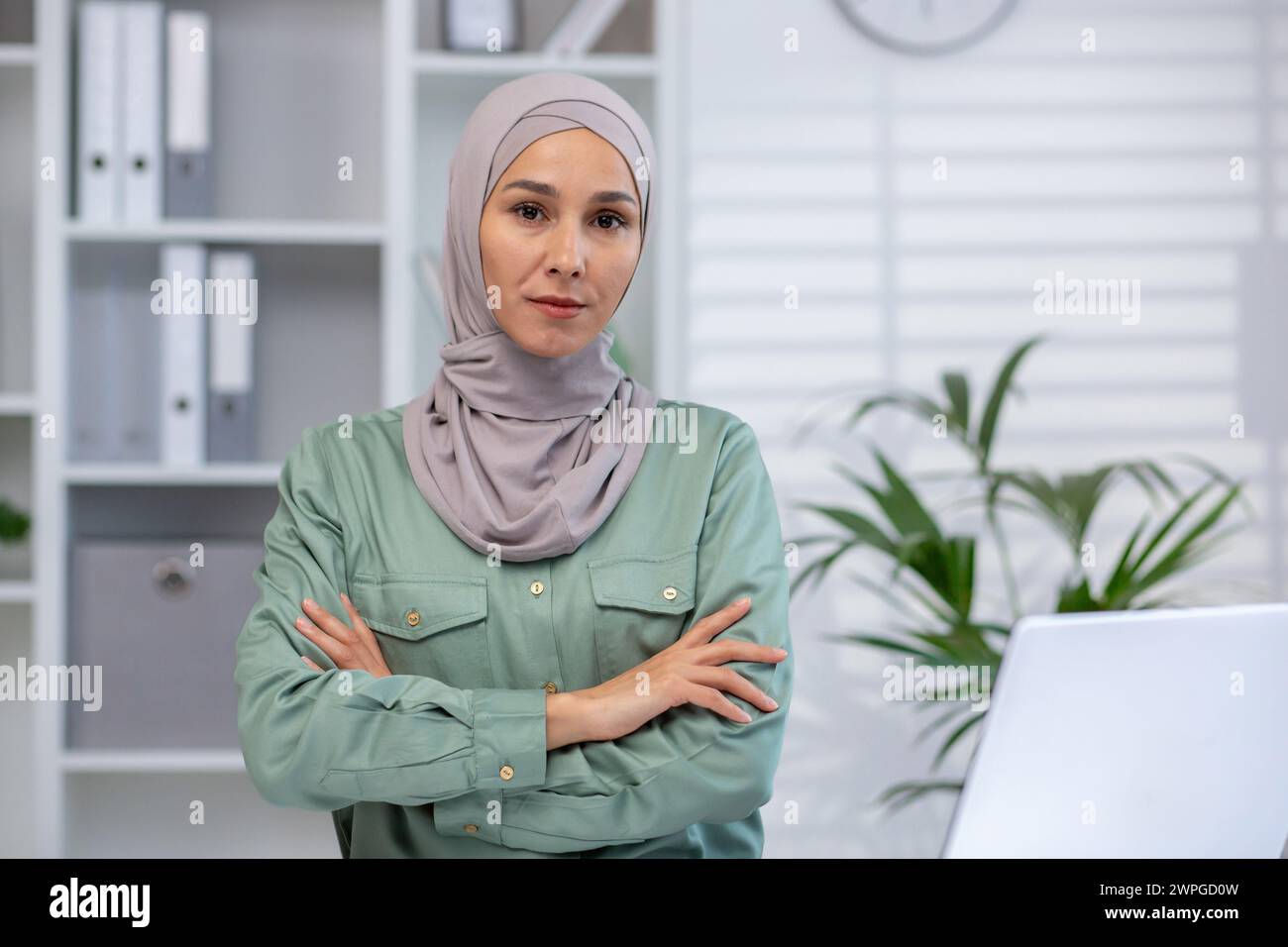 Professional young Muslim woman wearing a hijab stands confidently with ...