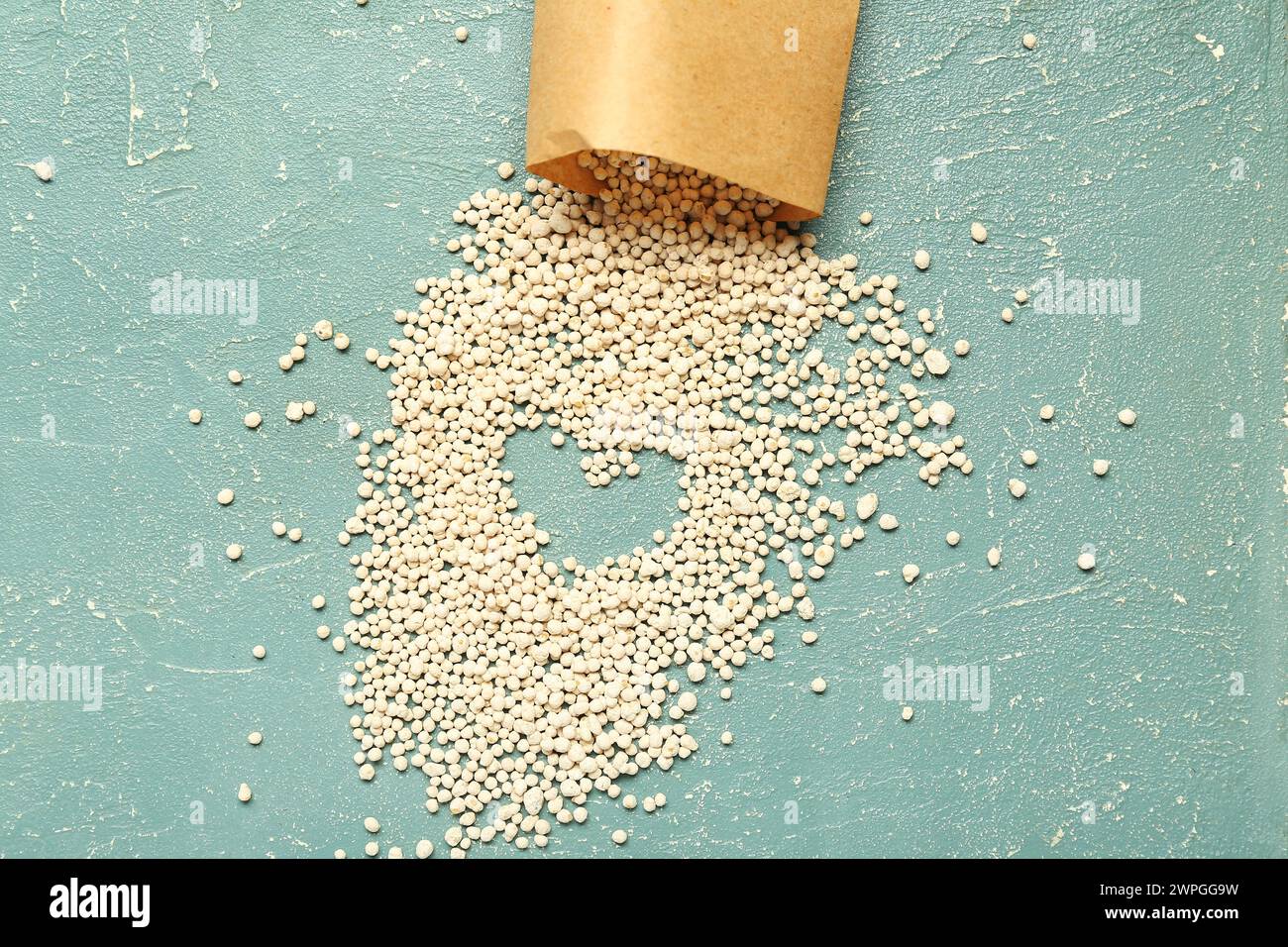 Paper bag with granular fertilizer in shape of heart on blue grunge ...