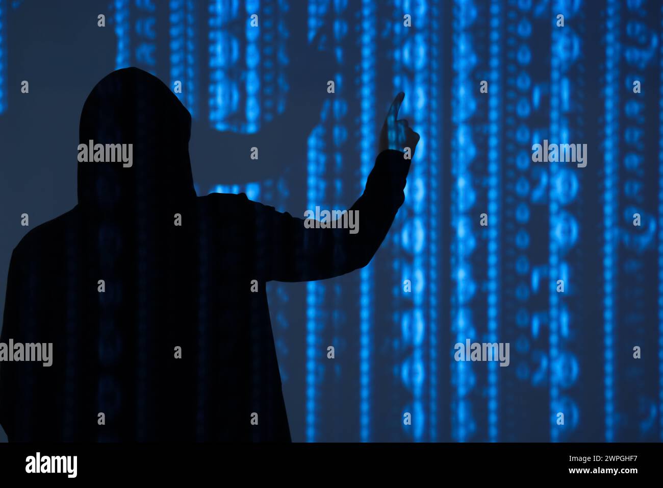 Hacker with projection of programming code pointing at something in ...