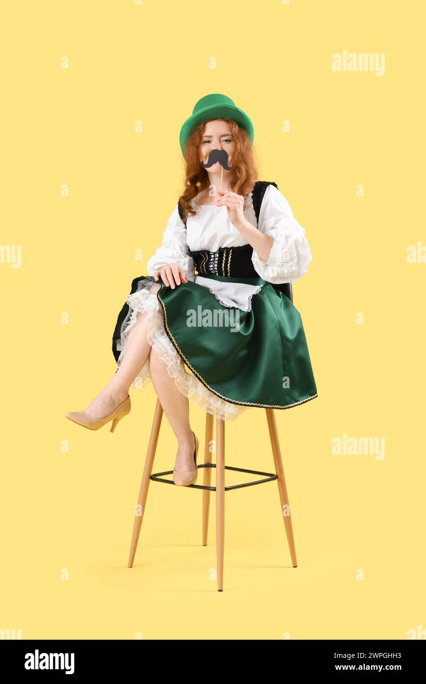 Young Irish waitress with paper mustache sitting on yellow background ...