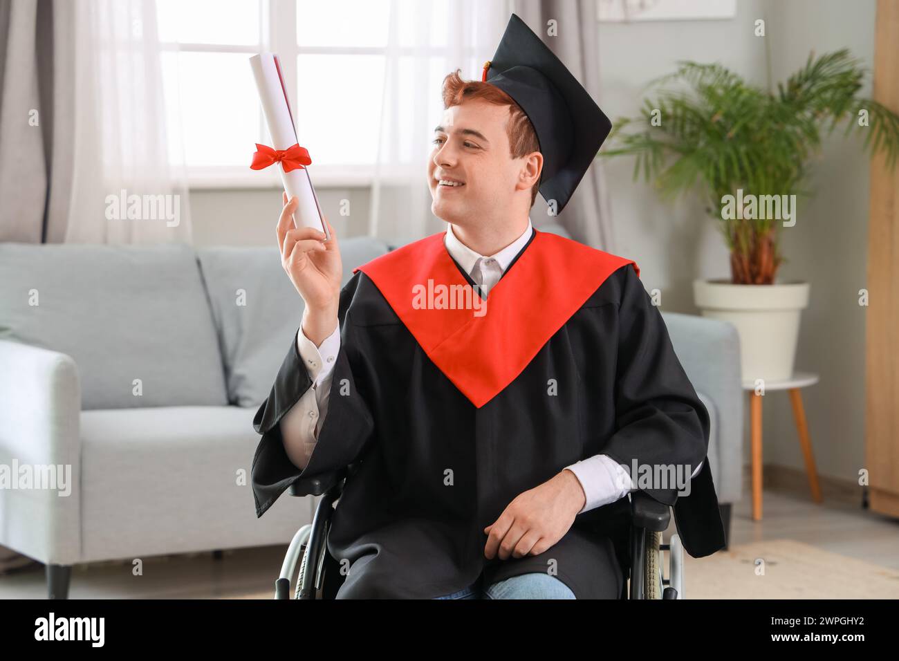 Male graduate in wheelchair with diploma at home Stock Photo - Alamy