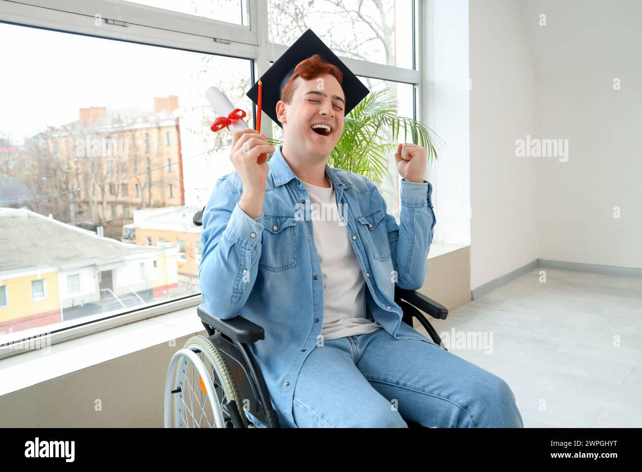 Happy male graduate in wheelchair with diploma at university hall Stock ...
