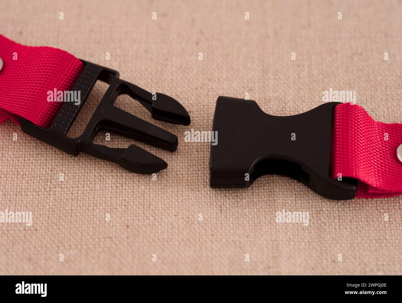 Two ends of a black contoured side release plastic buckle lying on a ...