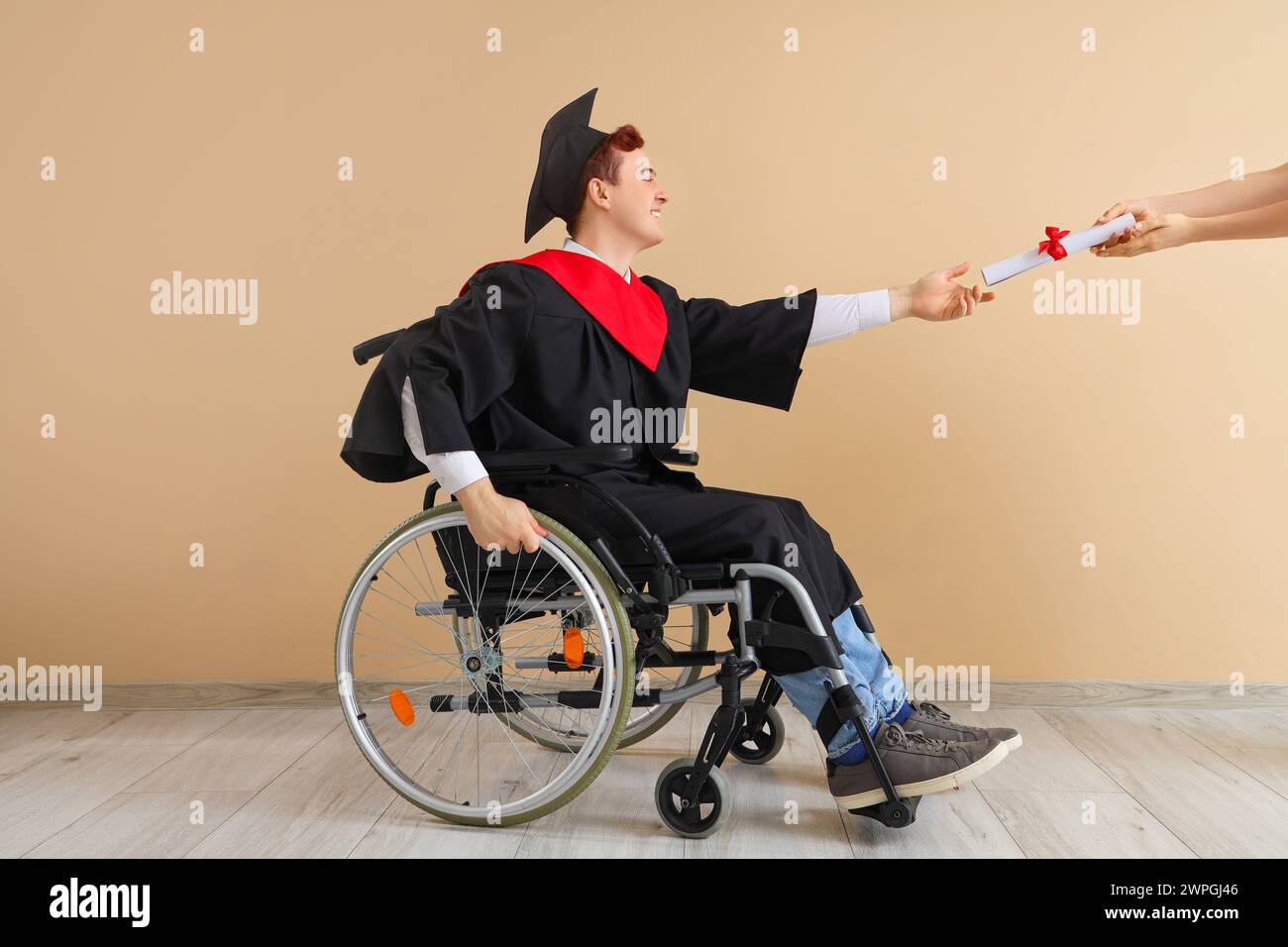 Male graduate in wheelchair receiving diploma near beige wall Stock ...