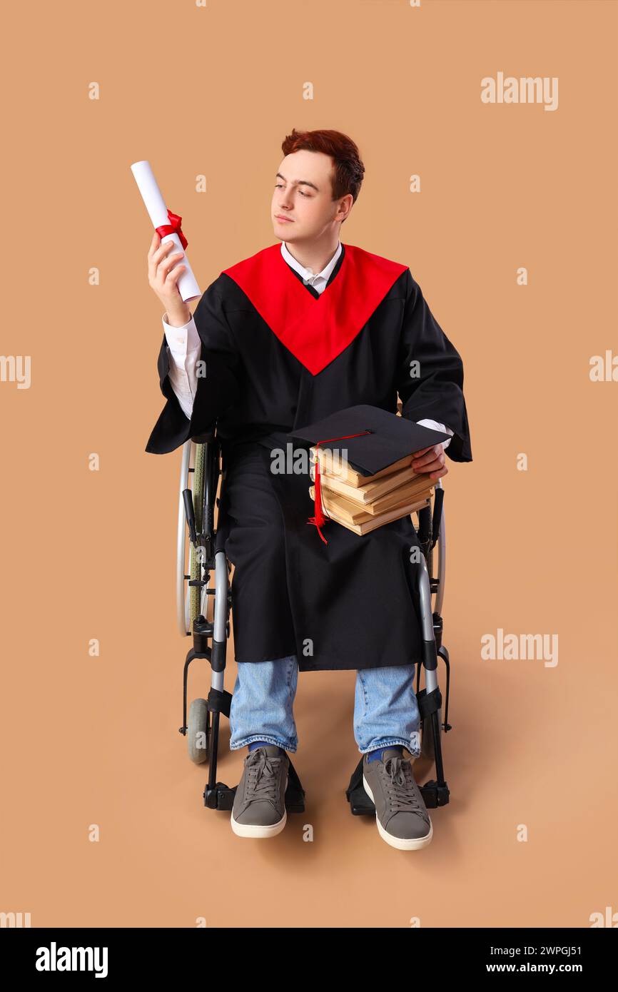 Male graduate in wheelchair with books and diploma on beige background ...