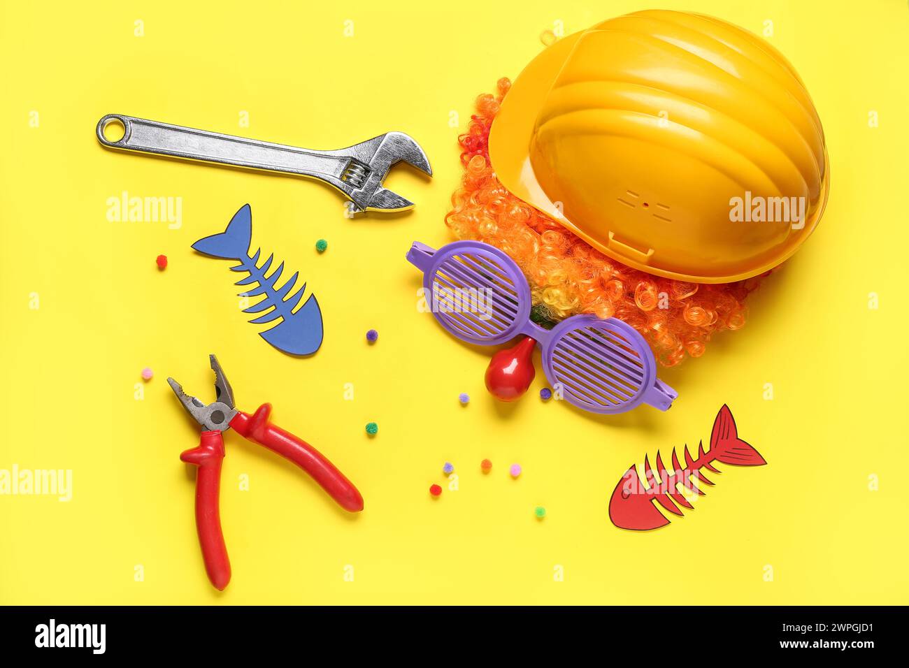 Mechanic items with clown wig, funny glasses and paper fishes on yellow ...