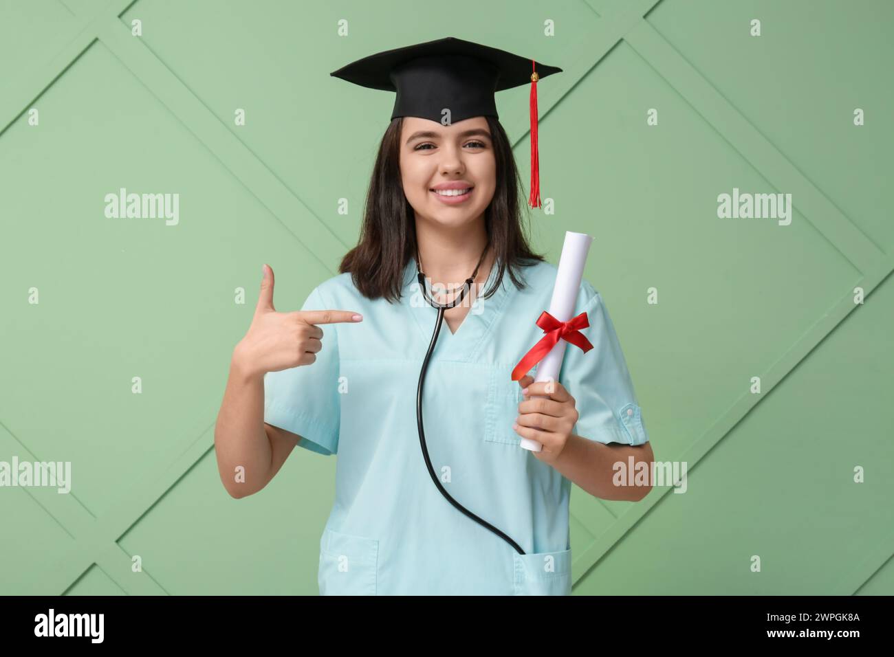 Happy female medical student in graduation hat pointing at diploma on ...