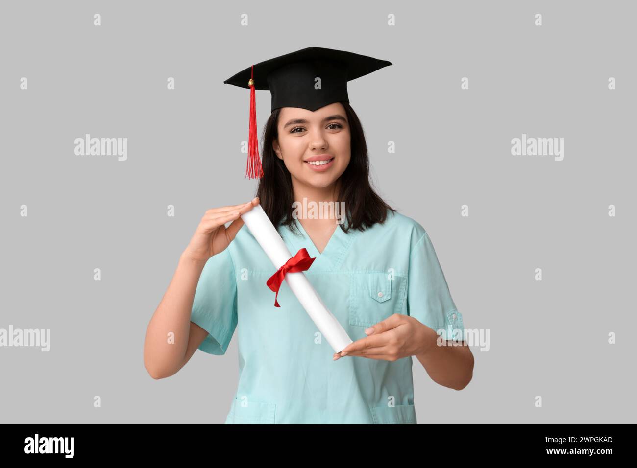Happy female medical student in graduation hat with diploma on white ...