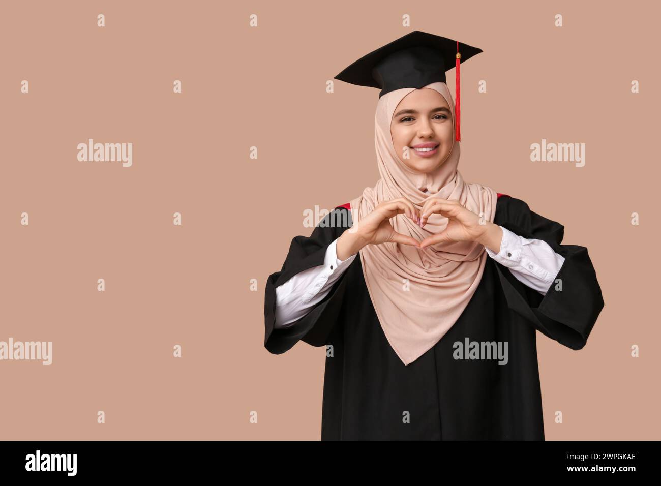 Happy Muslim female graduating student making heart with her hands on ...