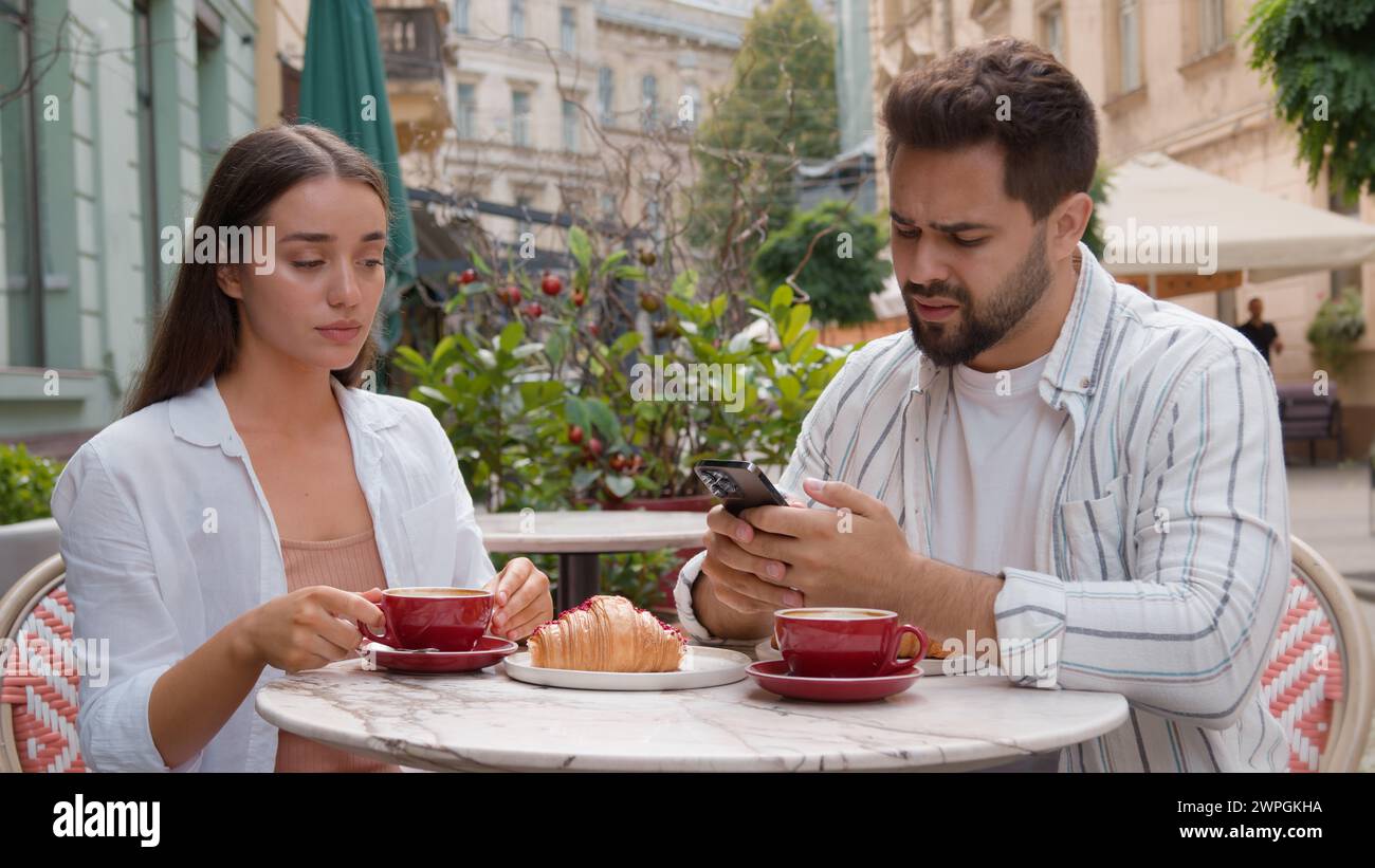 Caucasian couple eat breakfast in city cafe outdoors addicted busy man ...
