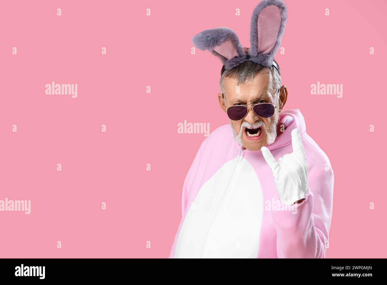 Cool senior man in Easter bunny costume showing "devil horns" gesture ...