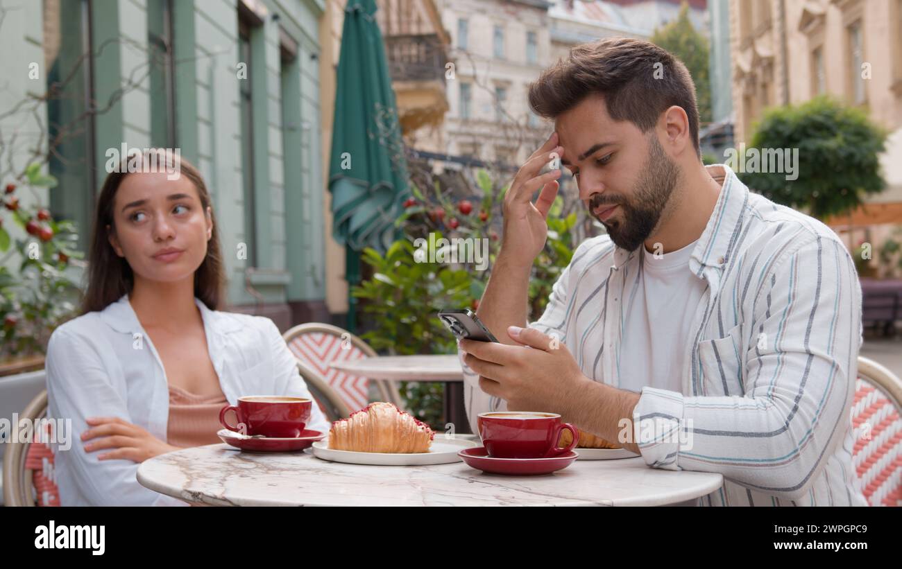 Caucasian couple eat breakfast in city cafe outdoors addicted busy man ...
