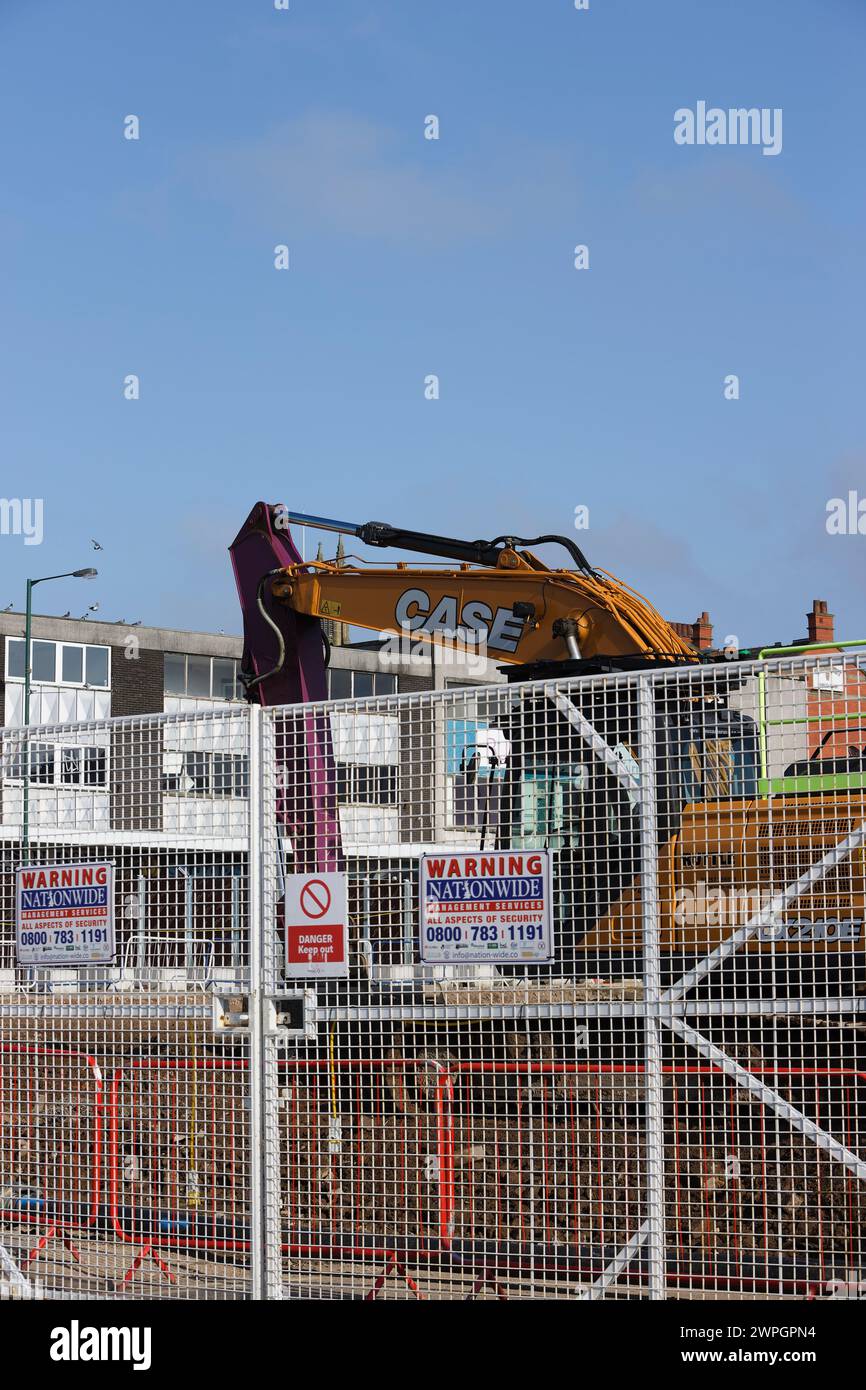 Tracked excavator behind fence with warning signs on construction site ...