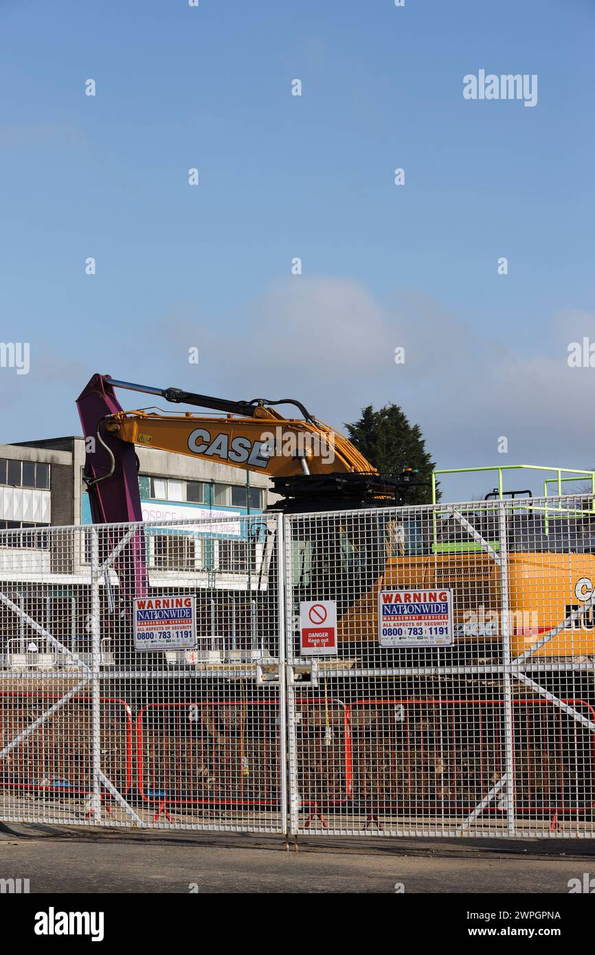 Tracked excavator behind fence with warning signs on construction site ...