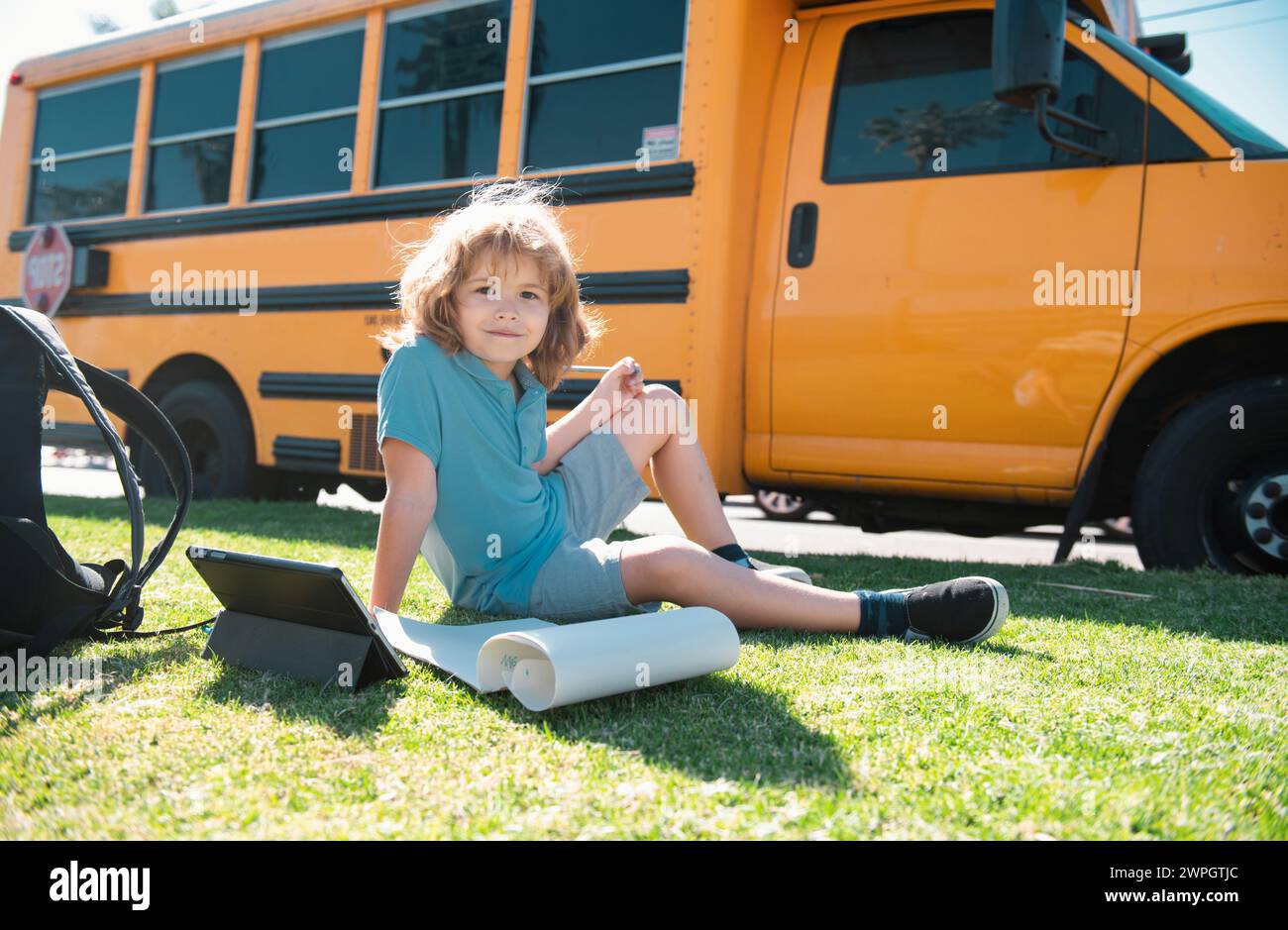 Smart schoolboy doing her homework with digital tablet at school park ...