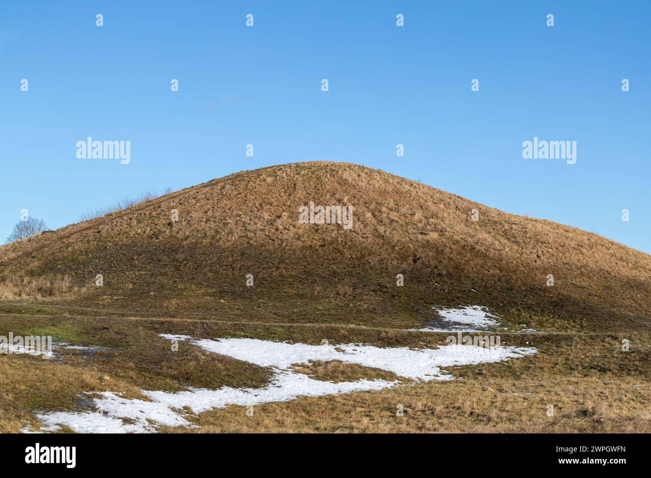 Burial mound covered with yellow grass in culture landscape. Wintertime ...