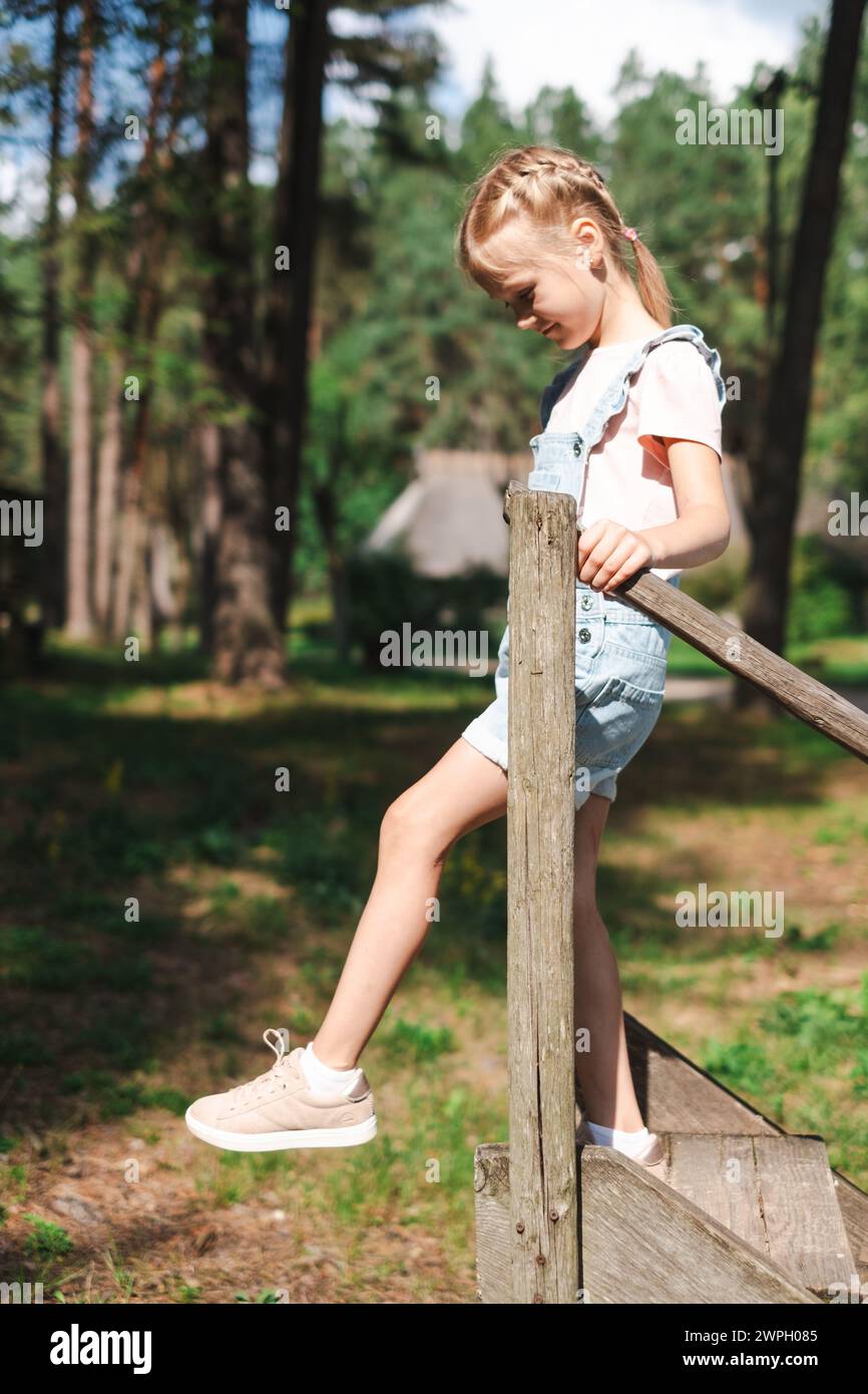 A curious girl in a green nature setting looks at the ground. This ...