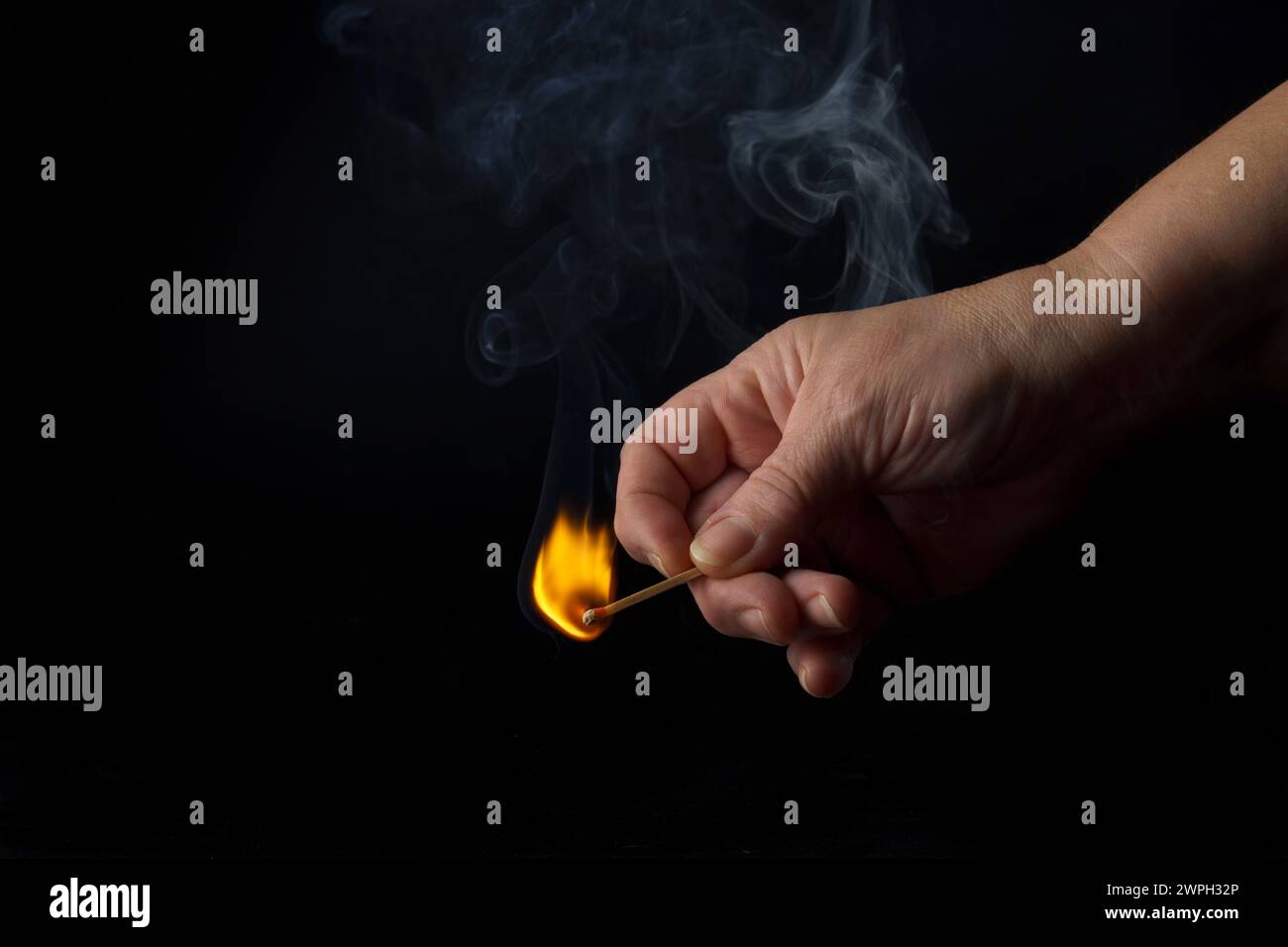 close-up of a woman's hand lighting a match isolated on black ...