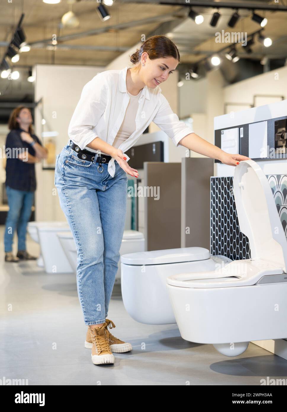 in plumbing department, female buyer checks for defects of toilet ...