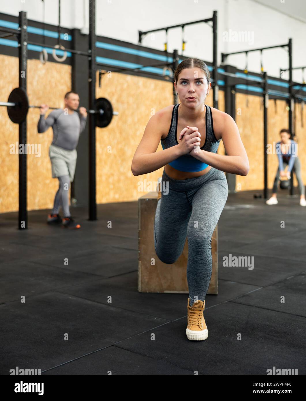 Young woman doing muscle stretching. CrossFit in group with other ...