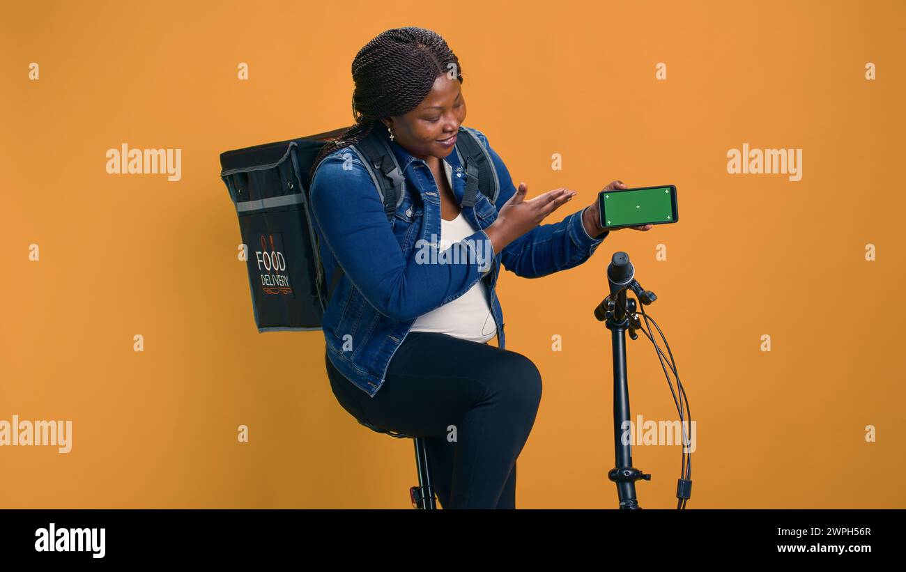 African american courier gripping cell phone showing green screen ...