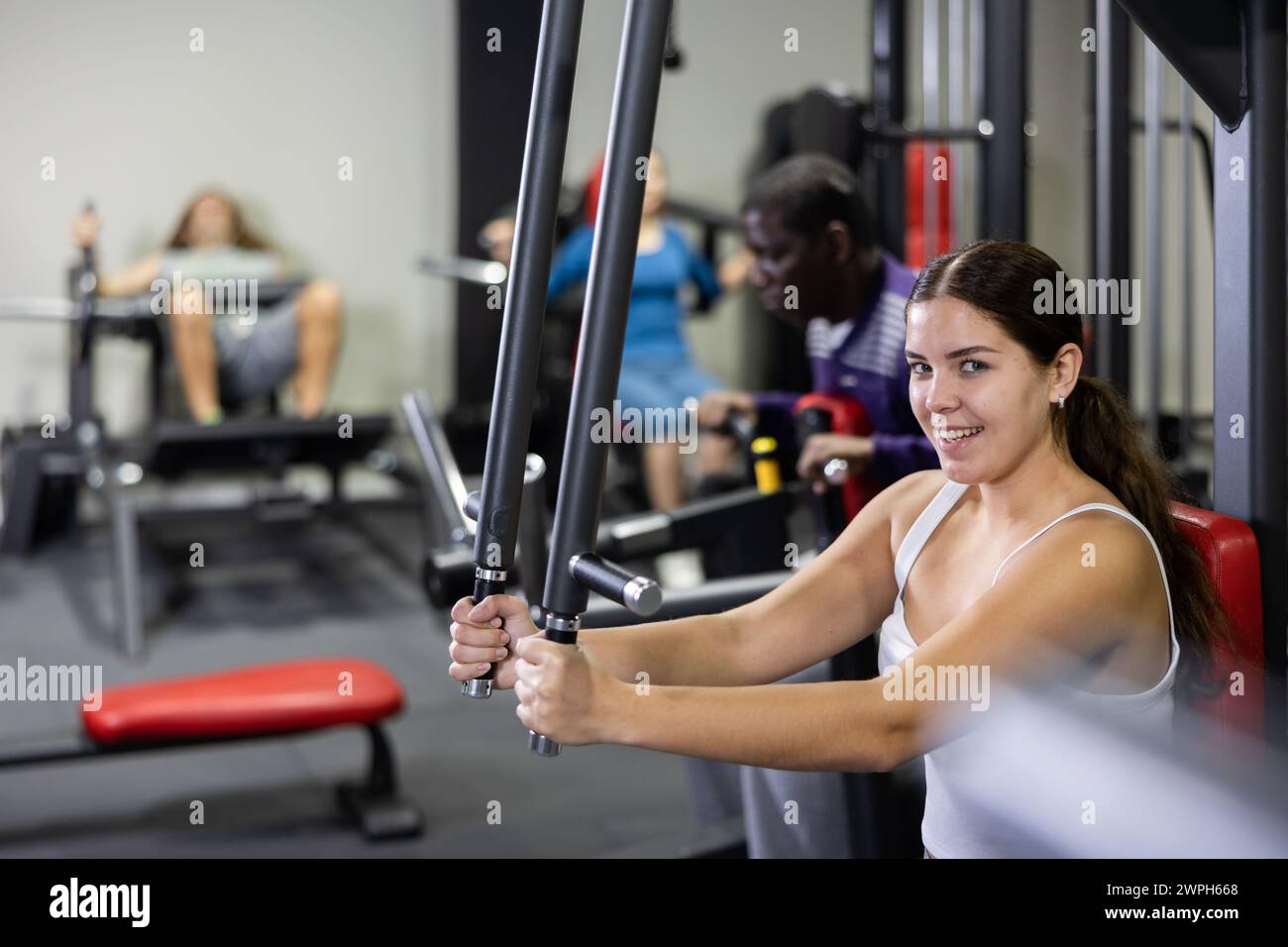 Sporty woman works on special simulator for development of pectoral ...