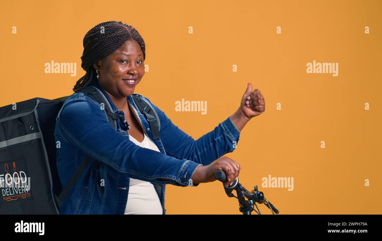 On yellow background, african american woman carrying food delivery bag ...