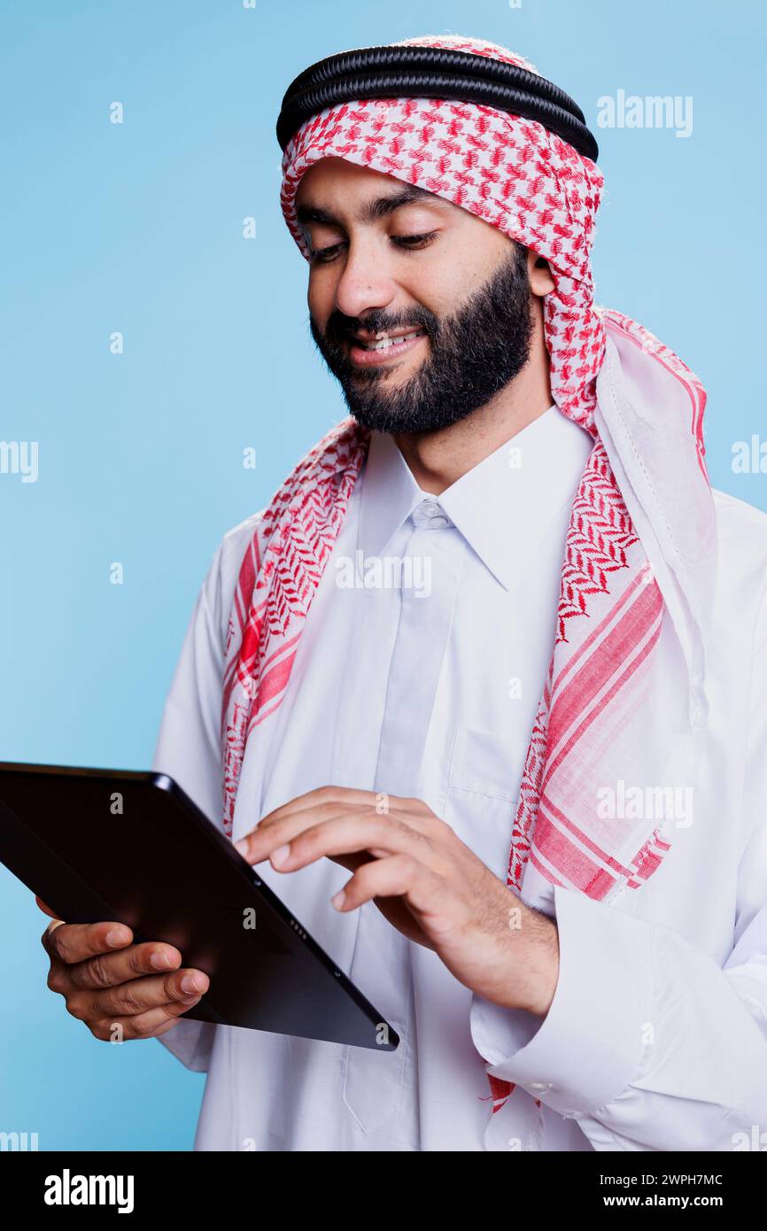 Smiling muslim person dressed in traditional clothes using digital ...