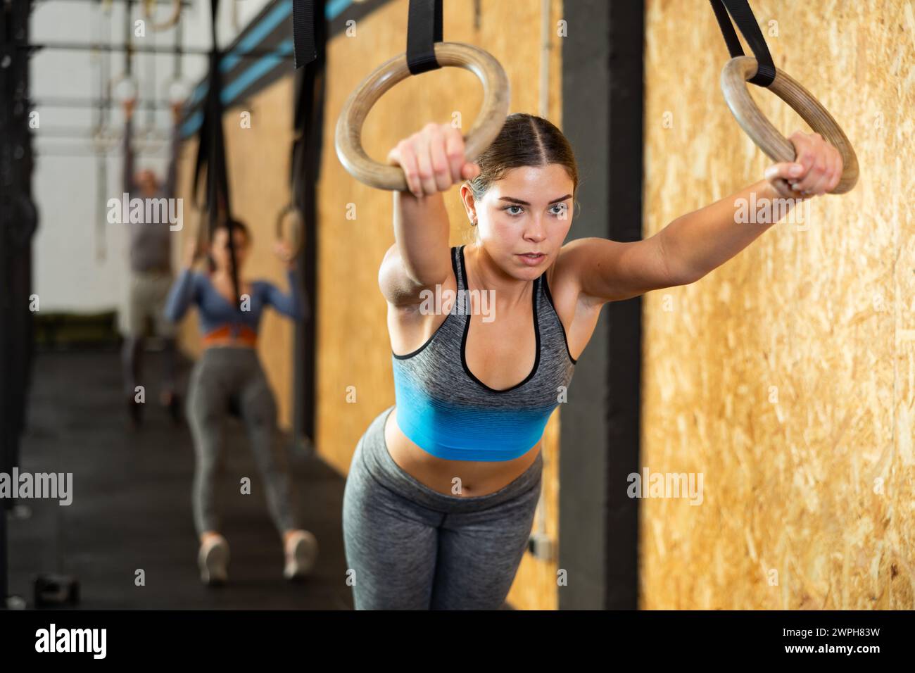 Young woman performs exercises using simulator machine with rings in ...