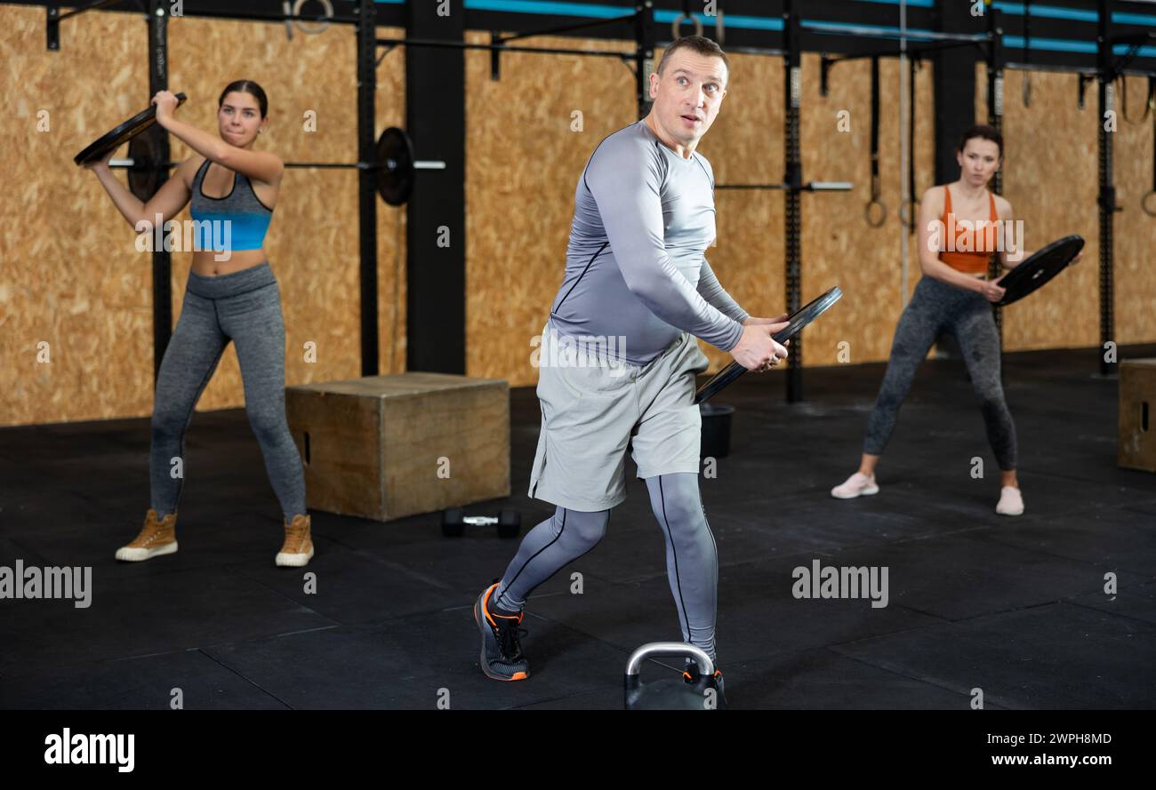Man does sports in gym and performs circular exercise using metal discs ...