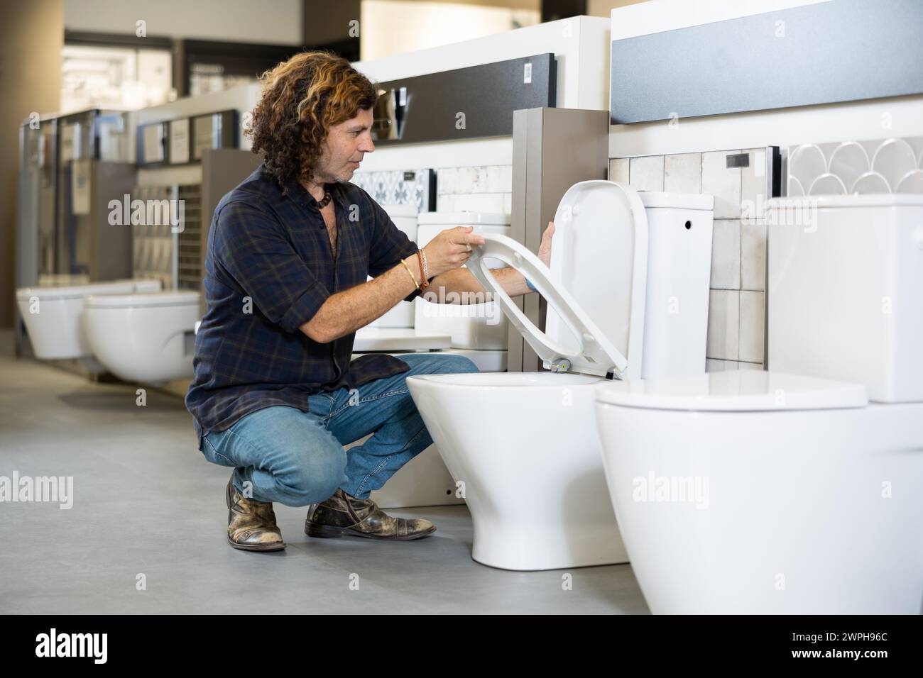 in plumbing department, male buyer checks for defects of toilet before ...