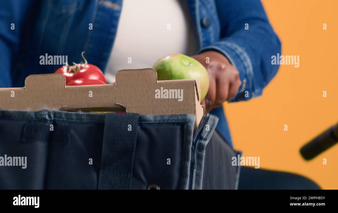 Female courier with african american ethnicity delicately moving basket ...