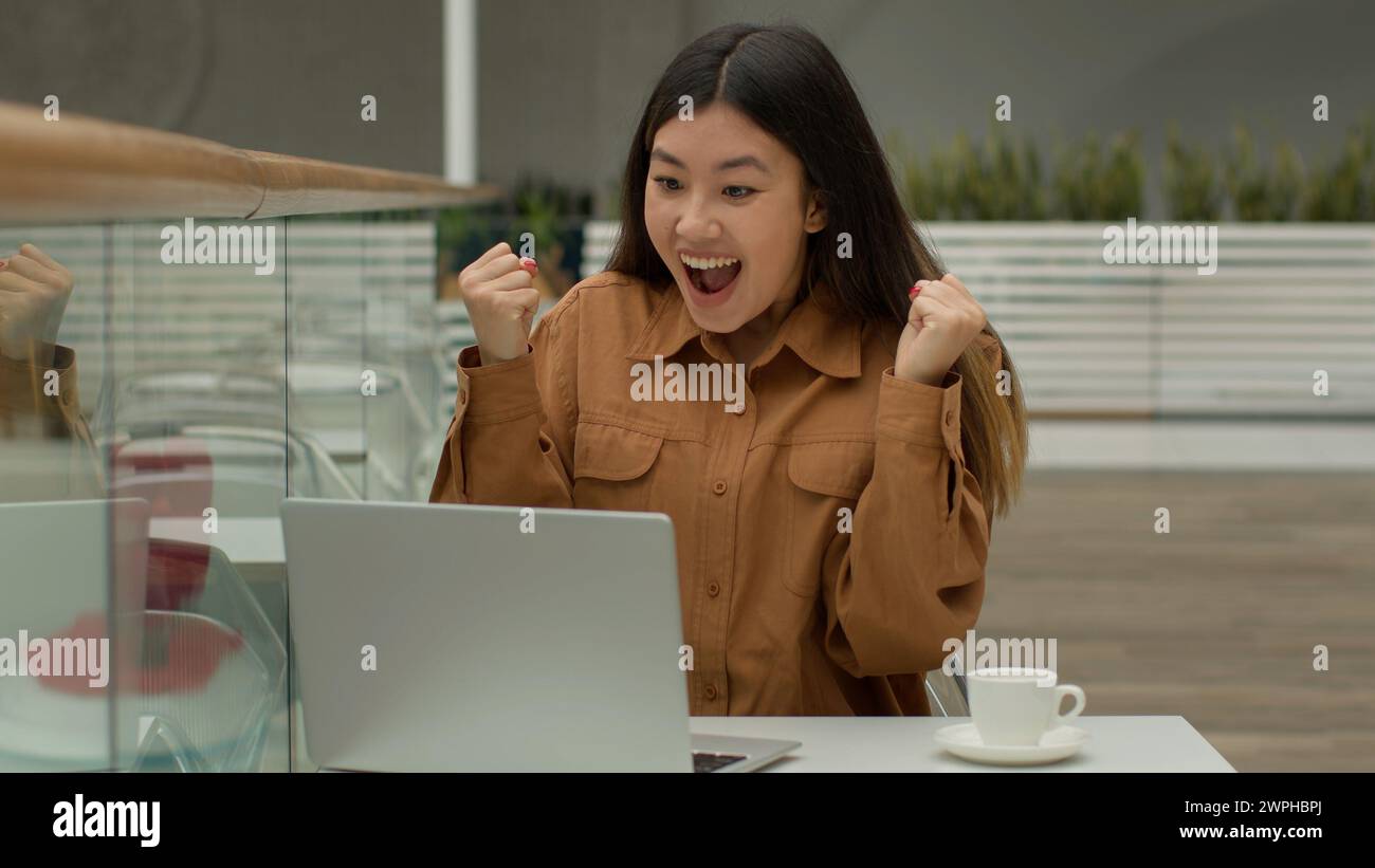 Happy shocked Asian woman businesswoman sit in cafe with laptop ...