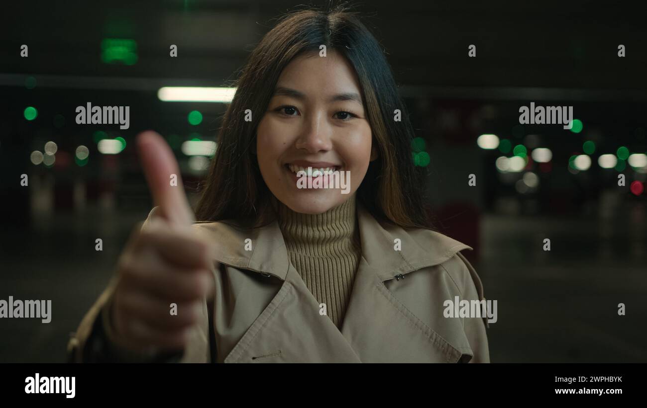 Happy Asian woman girl female shows thumb up finger gesture in parking ...