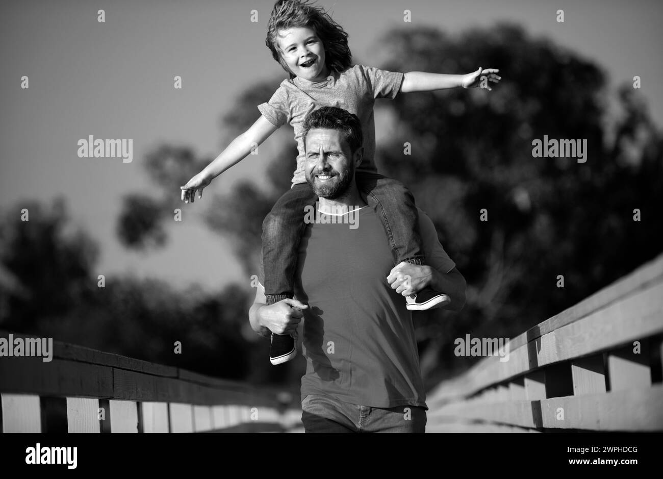 Father giving son ride on back in park. Portrait of happy father giving son piggyback ride on ...