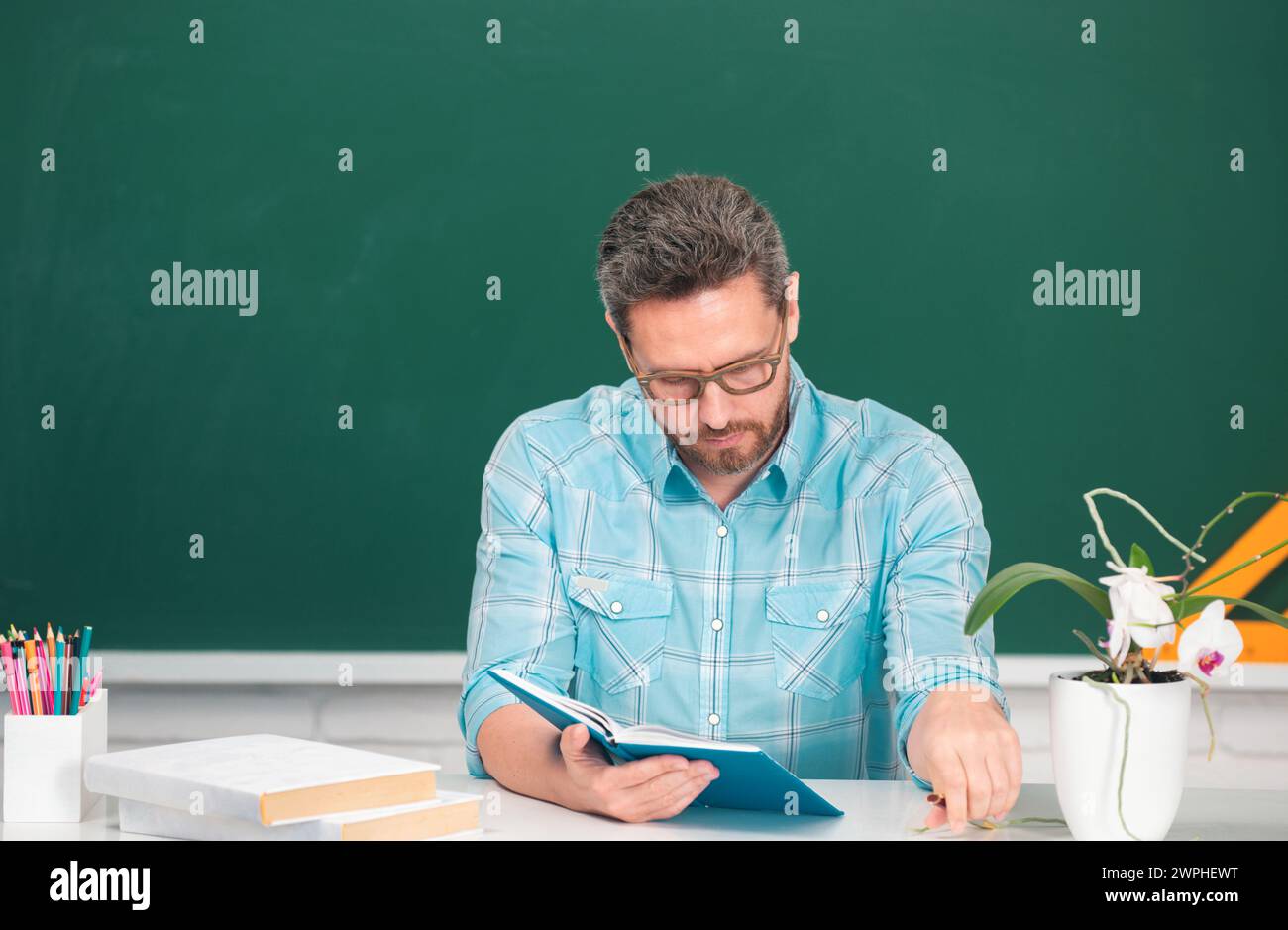 Portrait of confident caucasian male teacher in classroom. Middle aged ...