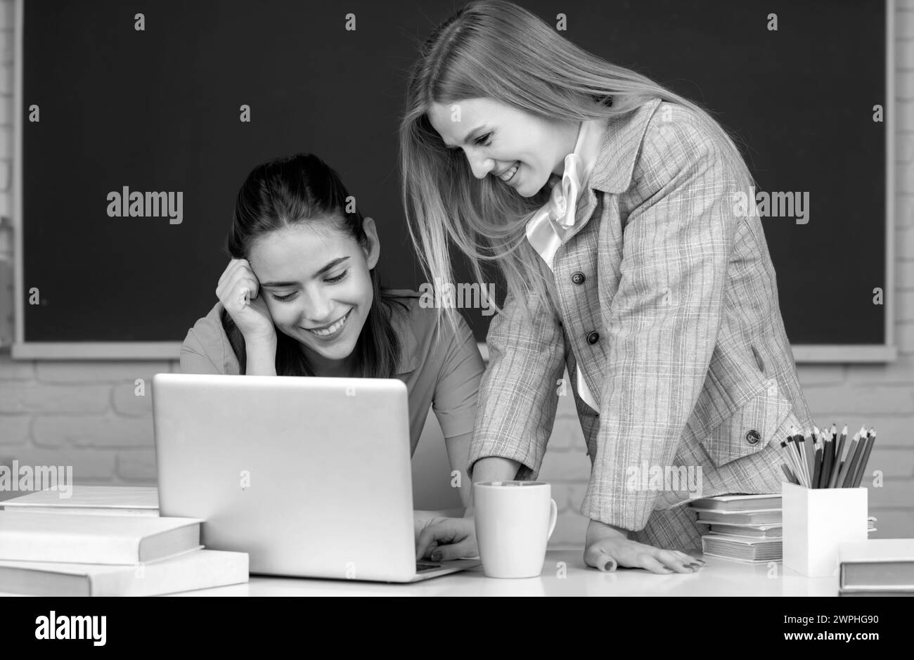 Students girls looking at laptop computer in classroom at school ...