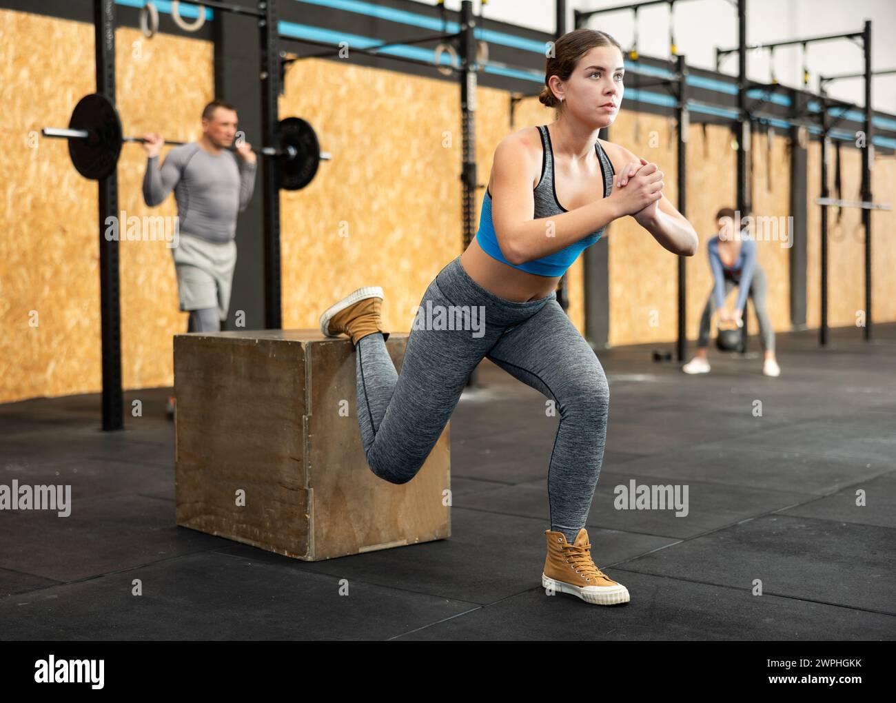 Young woman doing muscle stretching. CrossFit in group with other ...