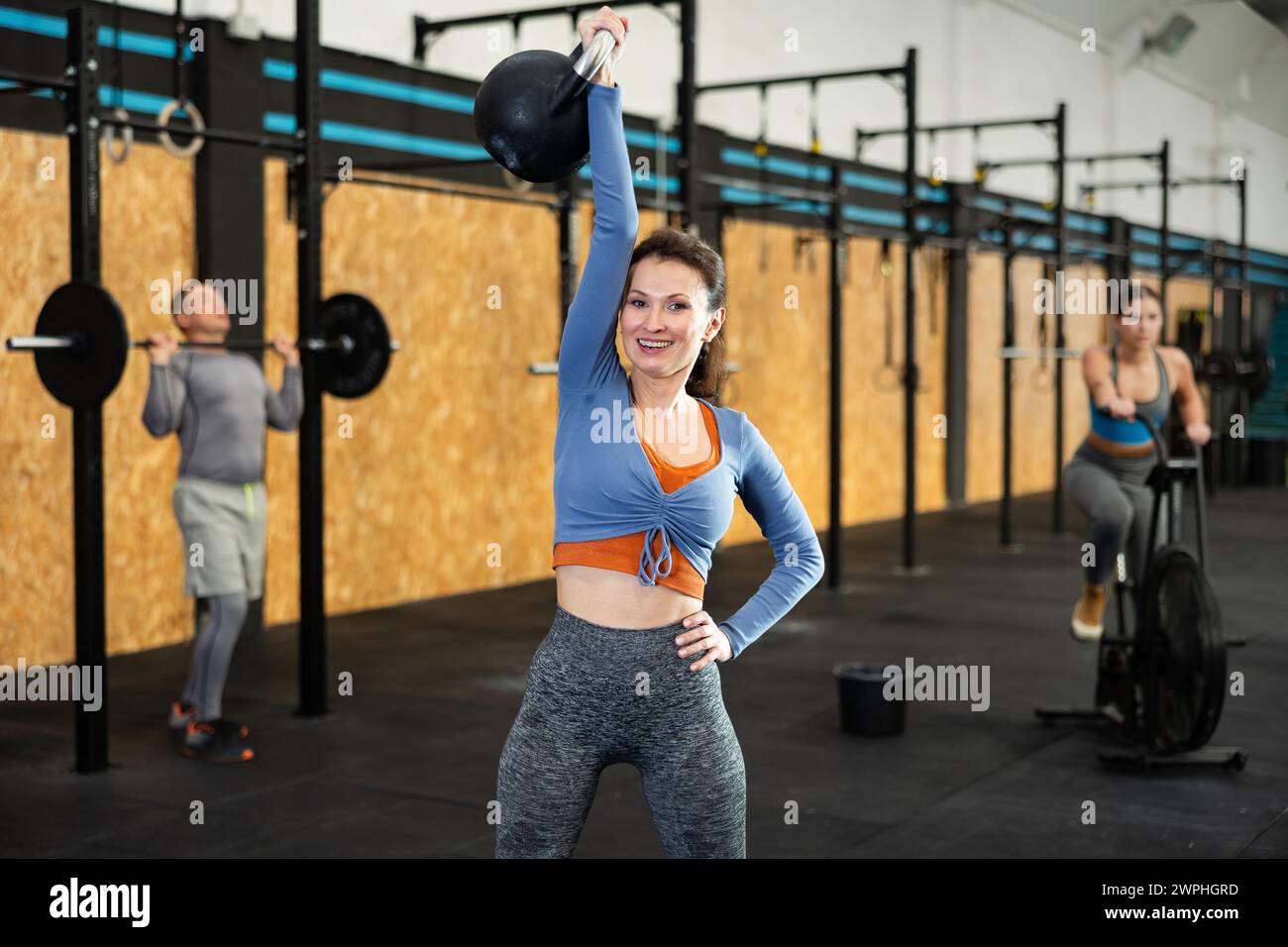 Slender woman trains muscles of arms and back using kettlebell ...
