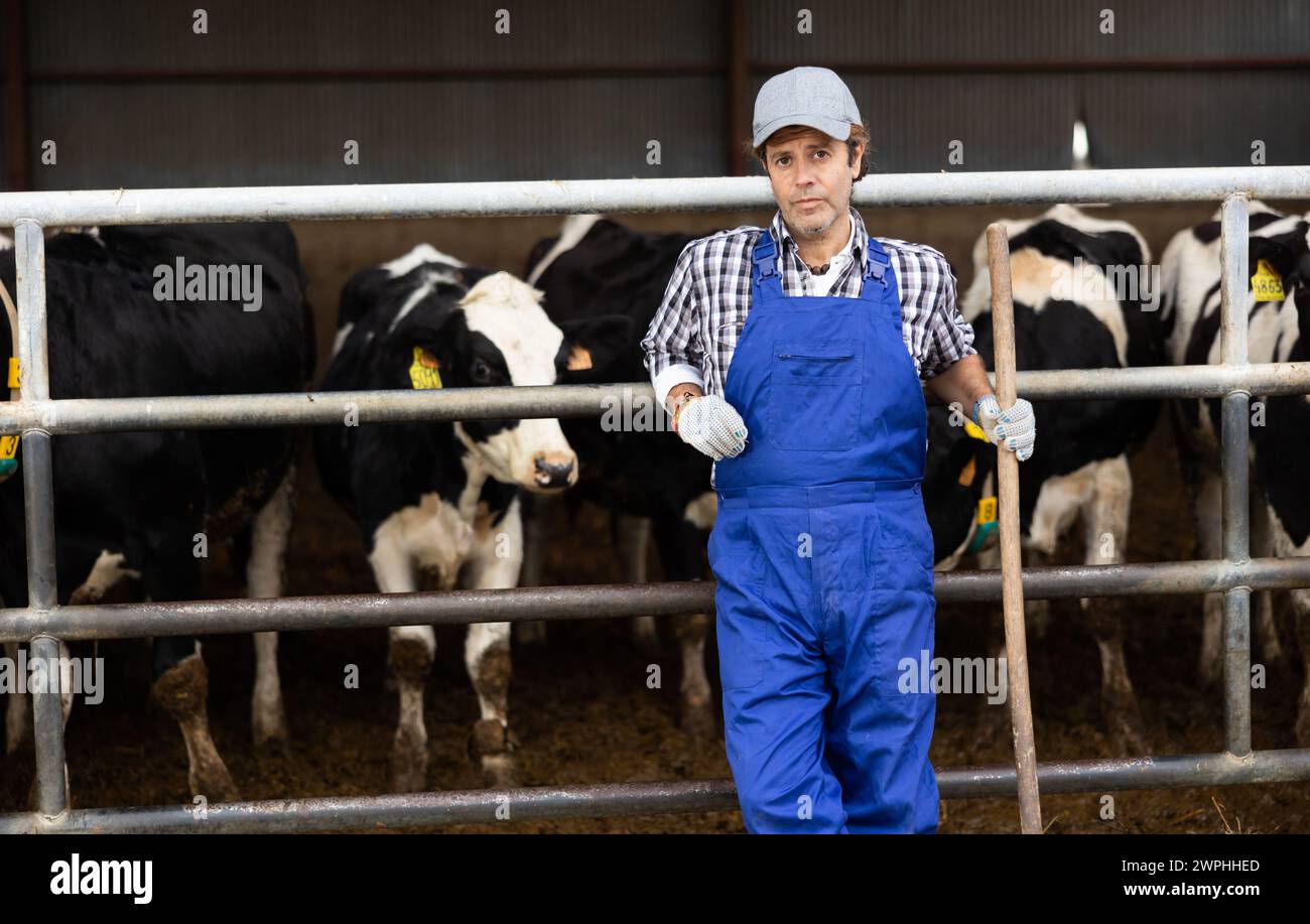 Farmer man stands with rake at cow farm Stock Photo - Alamy
