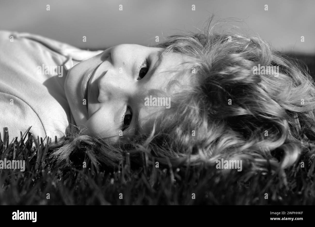 Carefree child laying on green summer meadow in the summer on nature ...