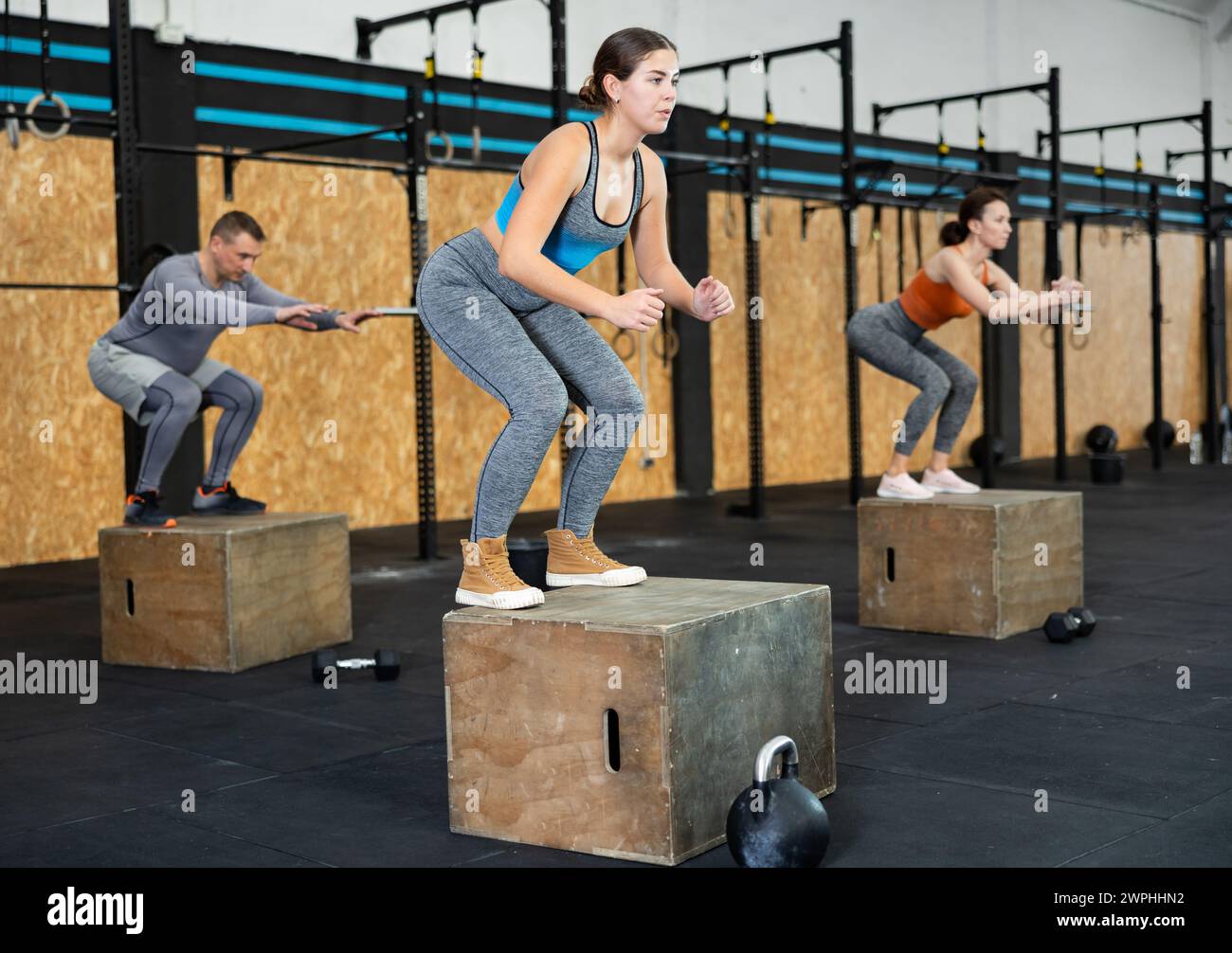 Young woman doing muscle stretching. CrossFit in group with other ...