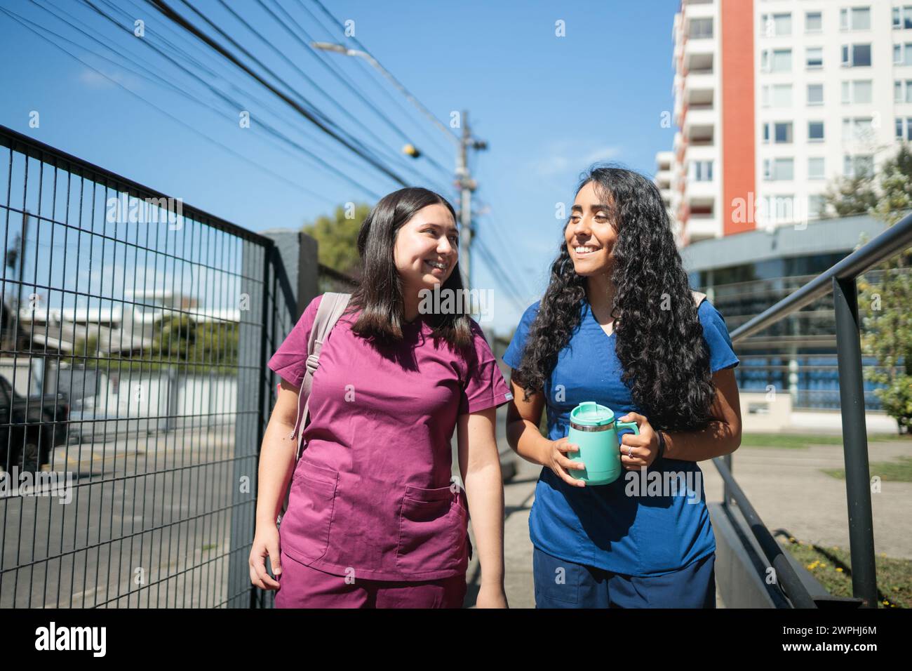 Two young latin nurses walking and talking after work. Female ...