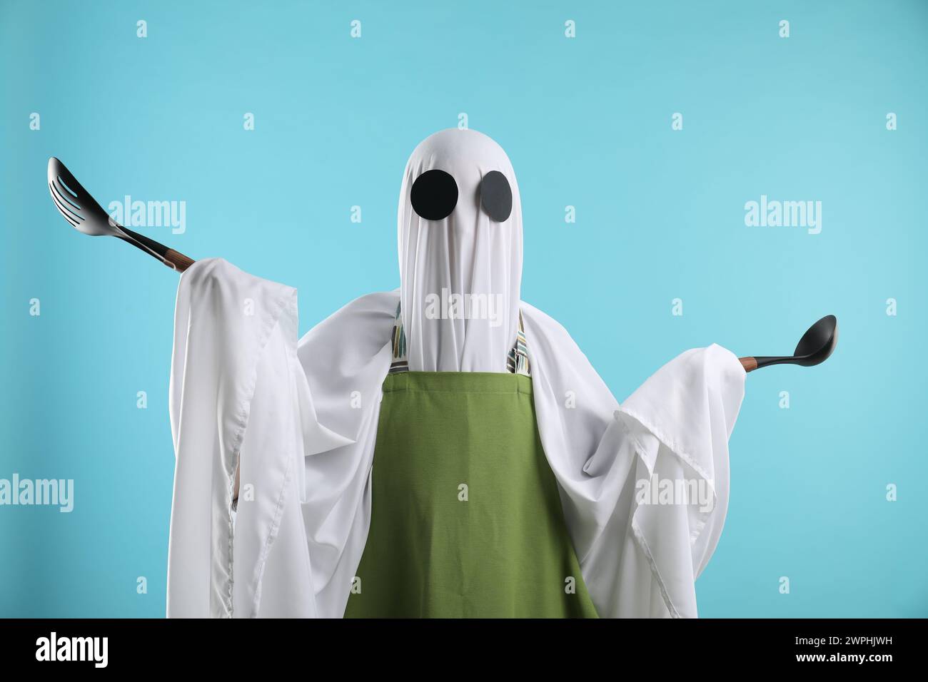 Woman in ghost costume and apron with kitchen set on light blue ...