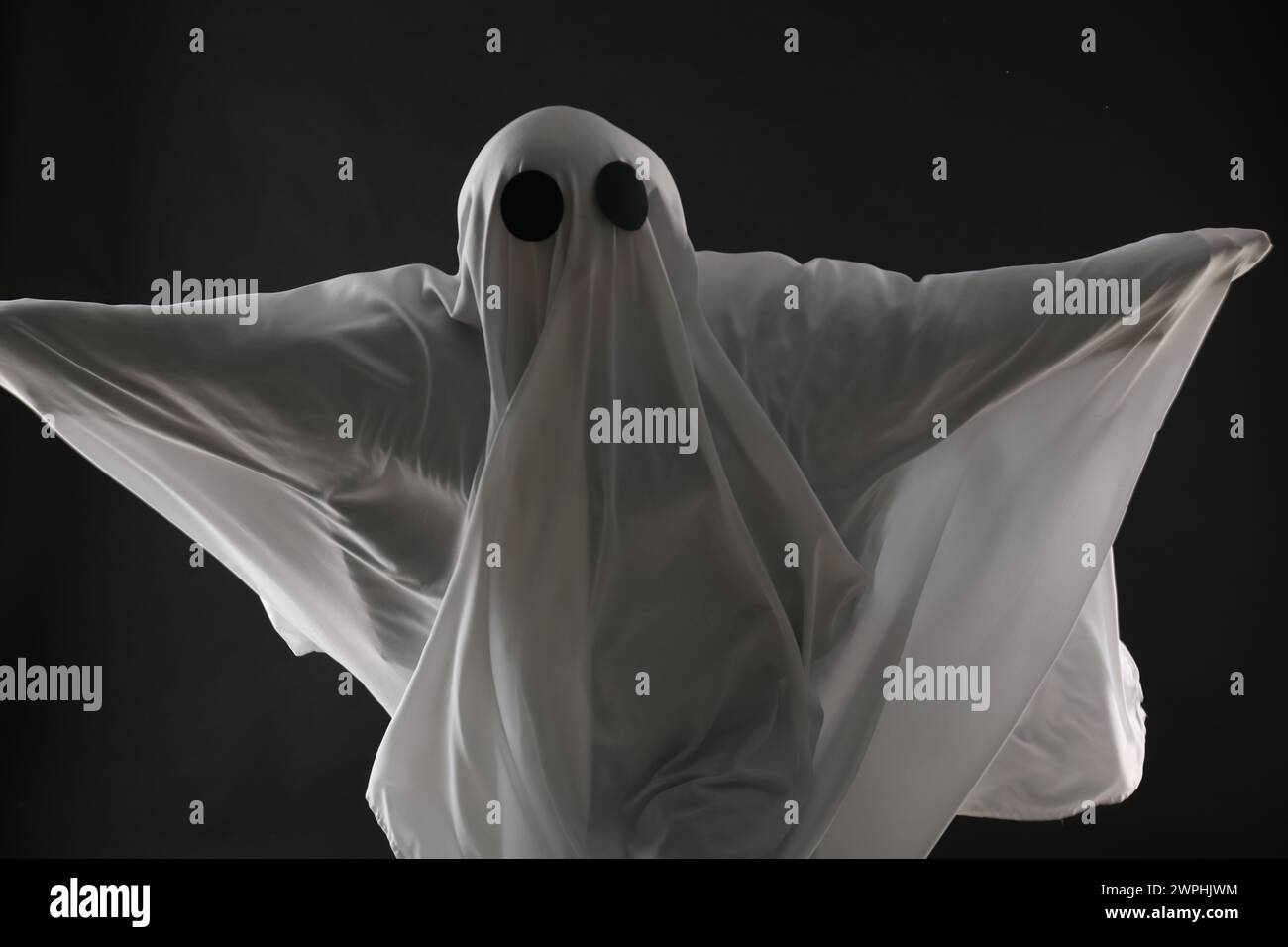 Creepy ghost. Person covered with white sheet on black background Stock ...
