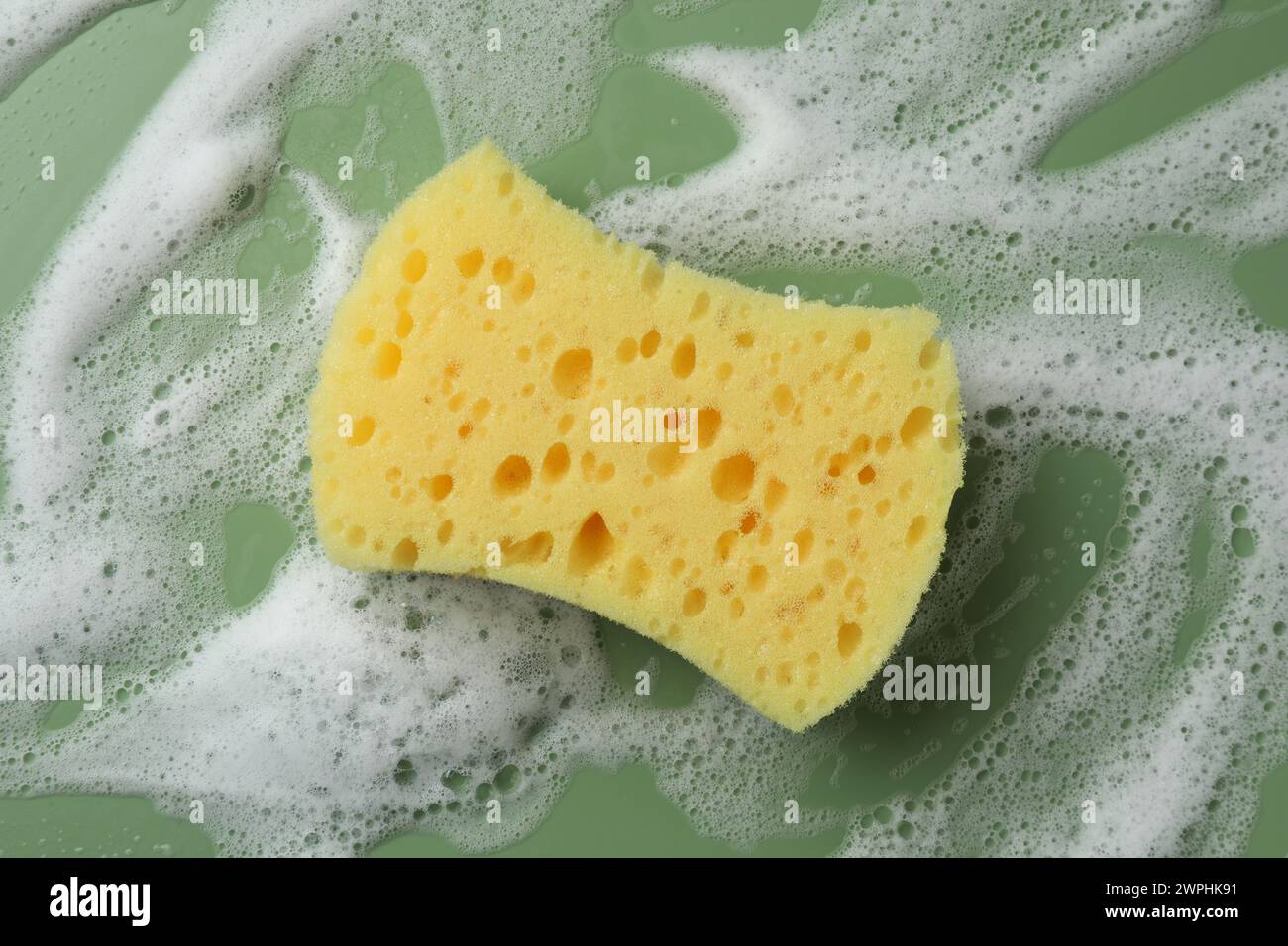 Yellow sponge with foam on green background, top view Stock Photo - Alamy